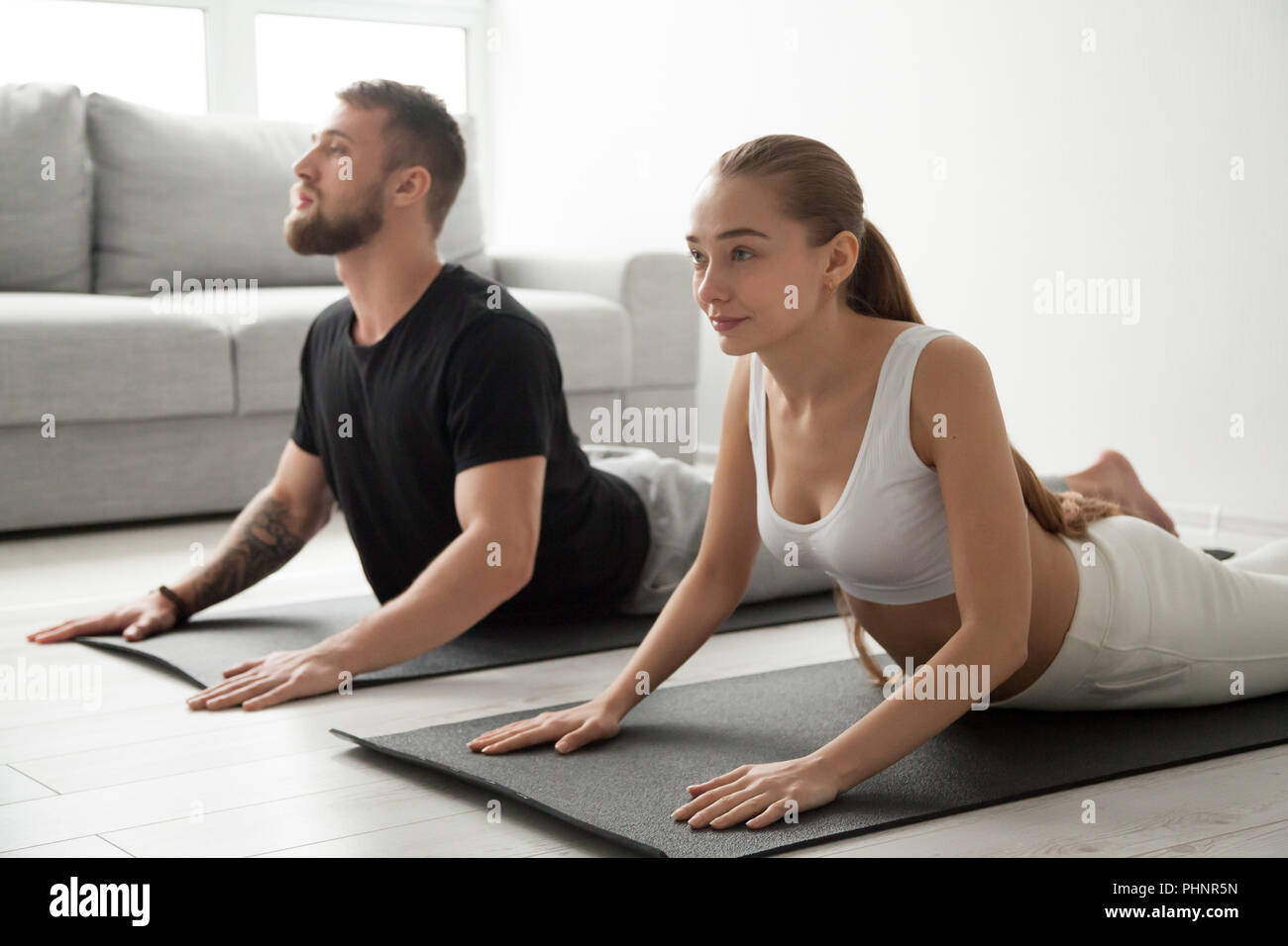 Calm millennial couple practicing yoga in cobra position Stock Photo ...