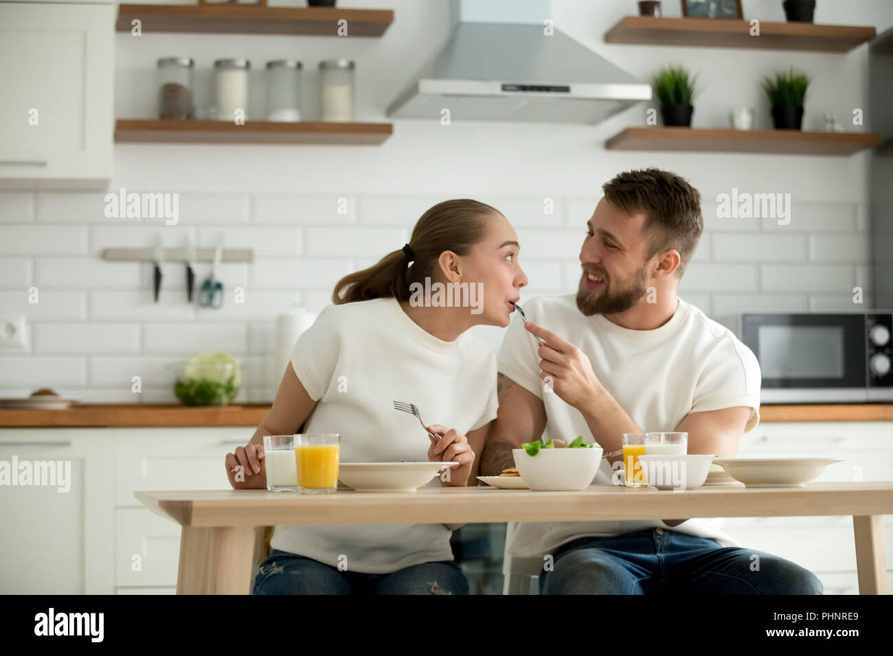 Millennial husband feeding wife with delicious breakfast Stock Photo ...