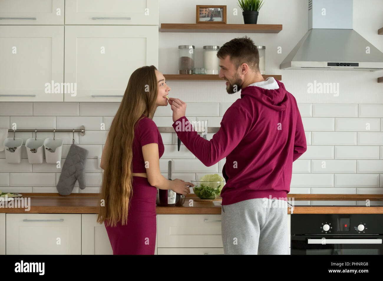 Loving boyfriend feeding girlfriend while cooking food together Stock ...