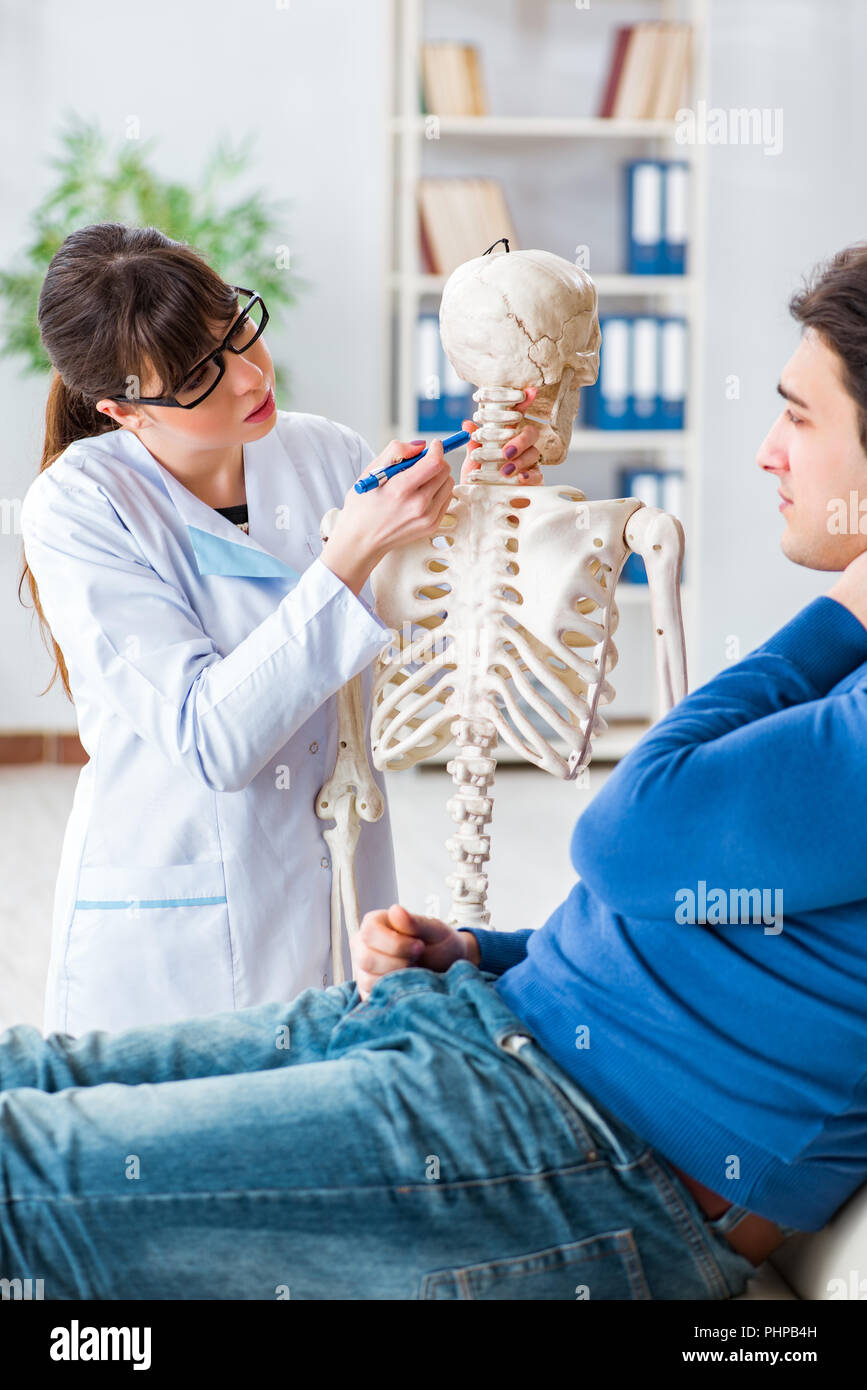 Doctor showing type of injury on skeleton to patient Stock Photo - Alamy