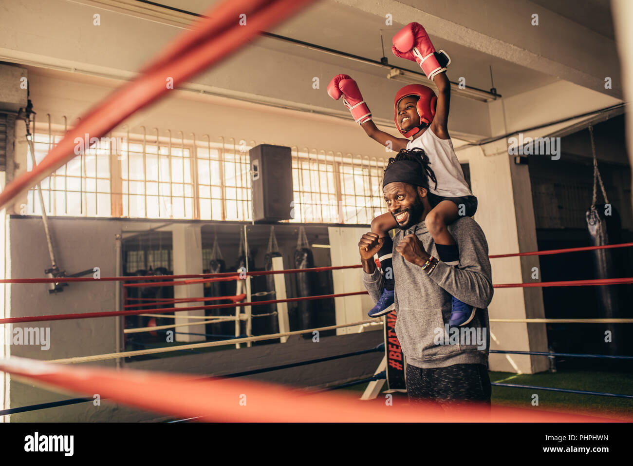 Trainer carrying a boxer kid on shoulders celebrating a win. Kid in ...
