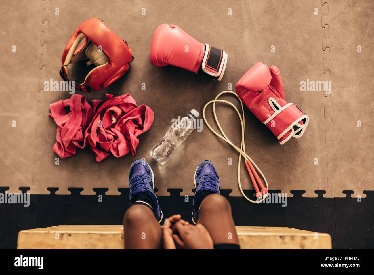 Close up of legs of a kid sitting on a block with boxing gloves ...