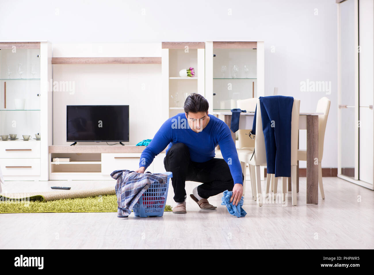 Young man collecting dirty clothing for laundry Stock Photo - Alamy