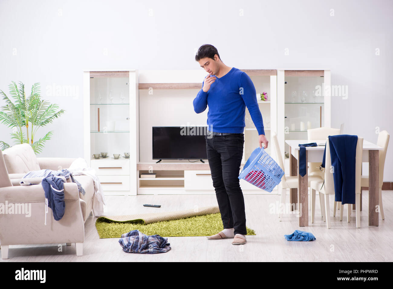 Young man collecting dirty clothing for laundry Stock Photo - Alamy