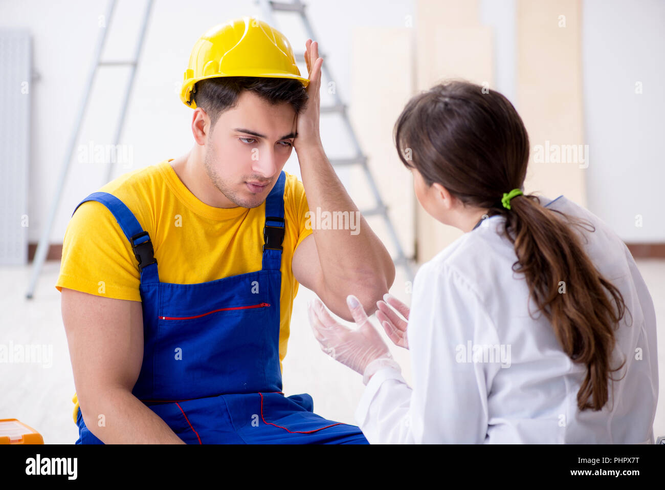 Doctor helping injured worker at construction site Stock Photo - Alamy