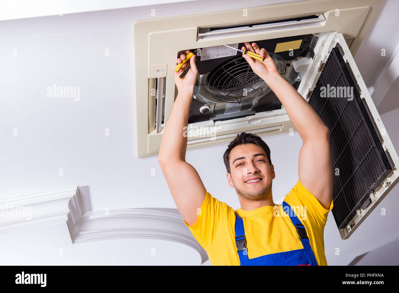 Repairman repairing ceiling air conditioning unit Stock Photo - Alamy