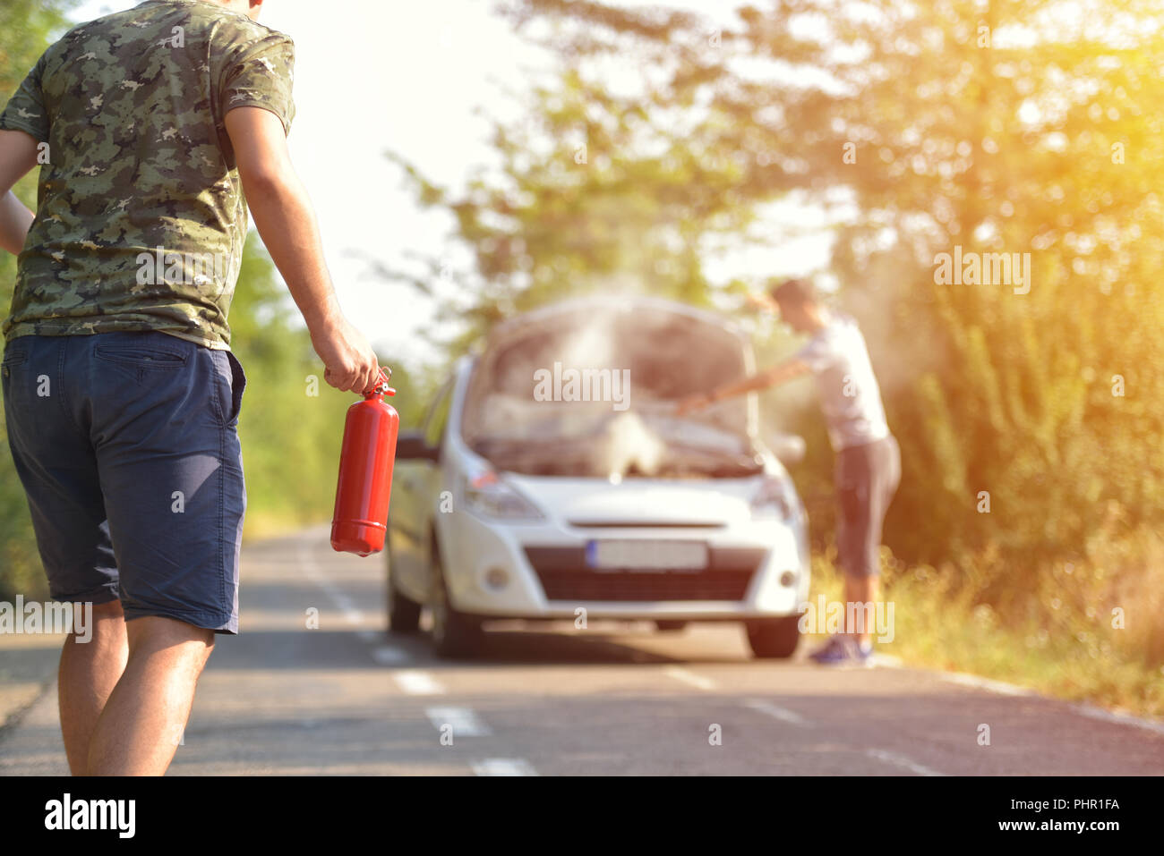 Brave man with fire extinguisher going to a car incident on the road ...