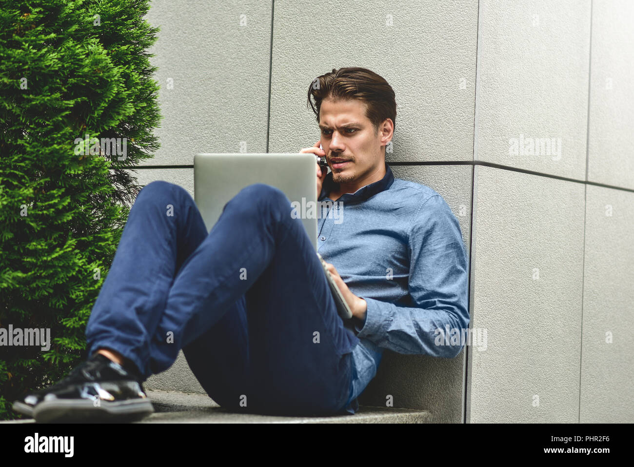 Young attractive guy who is smiling looking at his laptop screen during ...