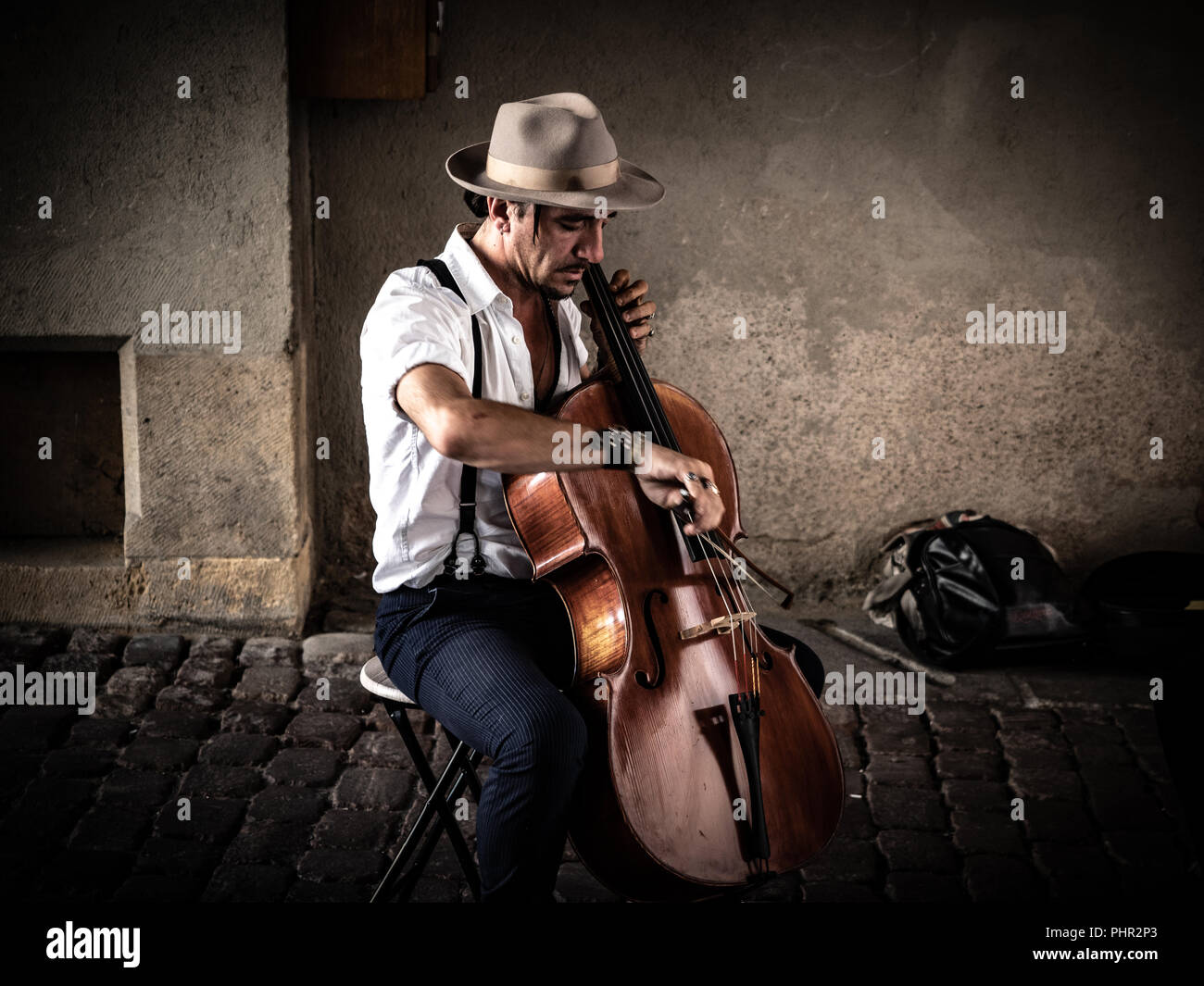 The Gypsy Cellist of Colmar busking to the public in a shaded alley on ...