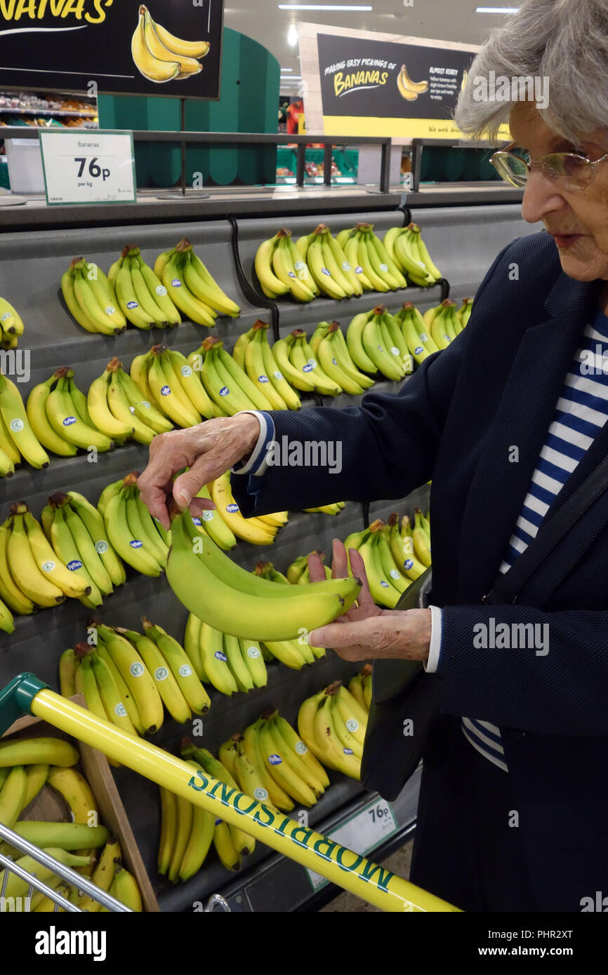 Lady buying bananas at her shopping in Morrisons supermarket aisle ...