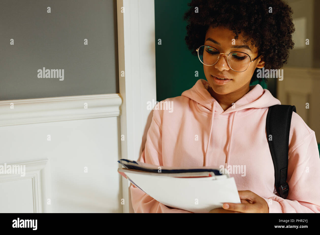 Student girl reading paper at wall indoors Stock Photo - Alamy