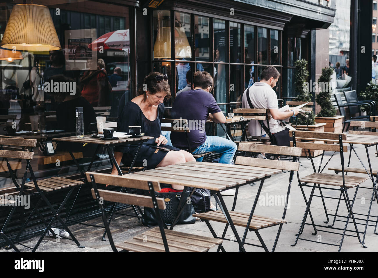 London, UK - July 24, 2018: People sitting at outdoor tables of a cafe ...