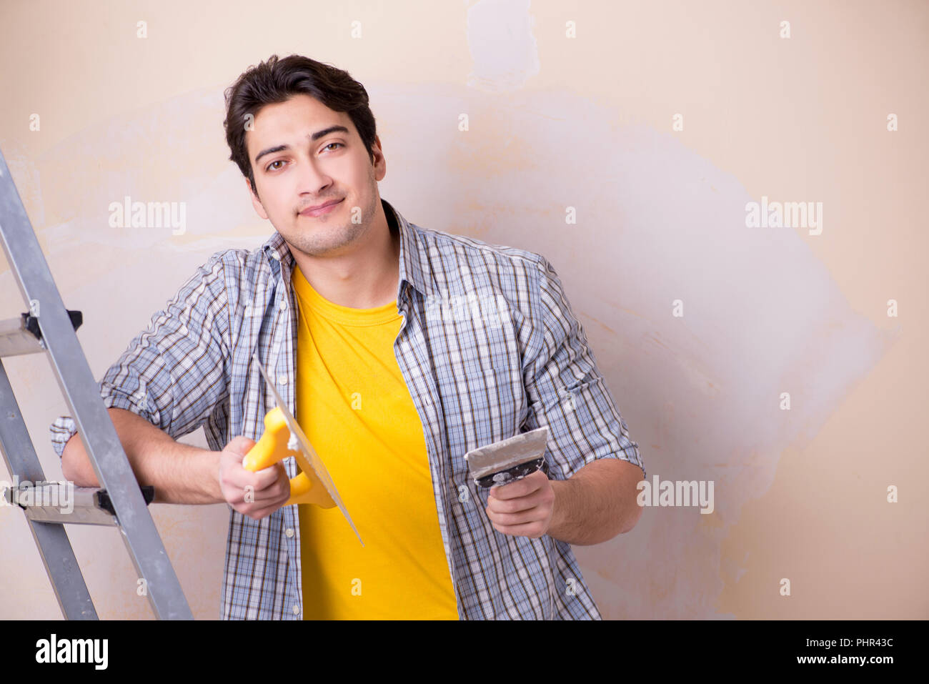 Young man applying plaster on wall at home Stock Photo - Alamy