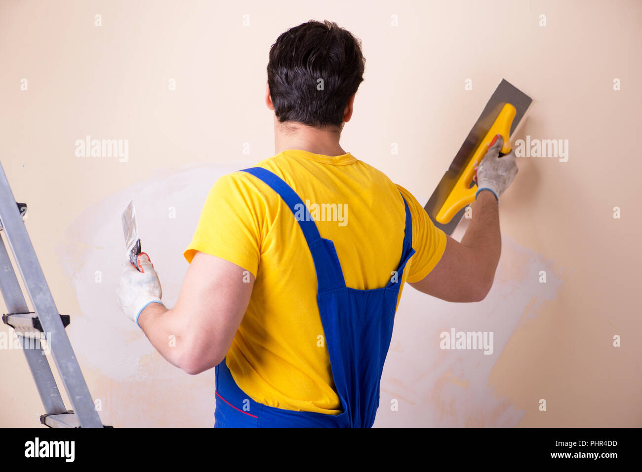 Young contractor employee applying plaster on wall Stock Photo - Alamy