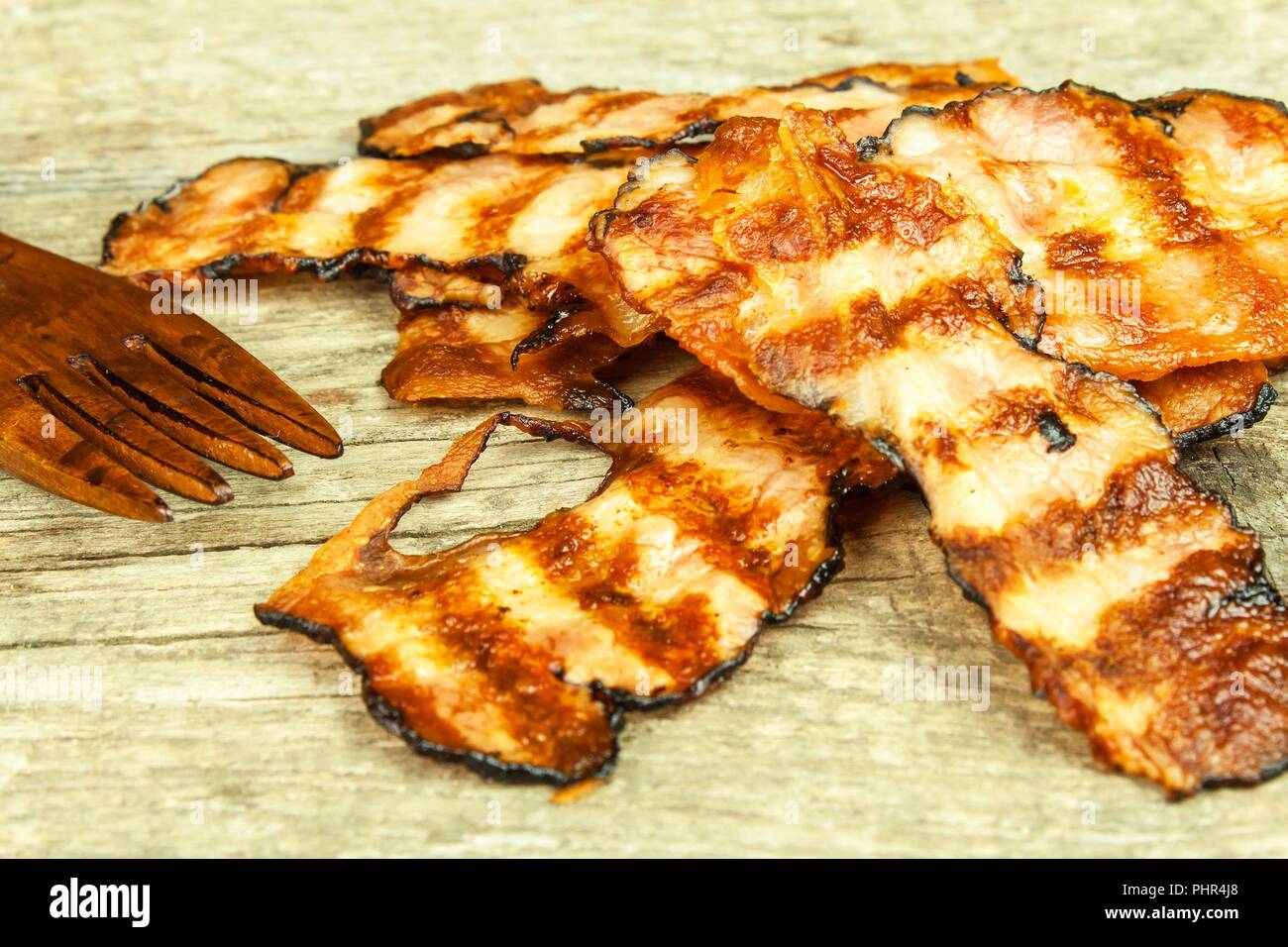 Grilled bacon. Crispy Cooked Bacon On Wooden Table. Unhealthy food ...