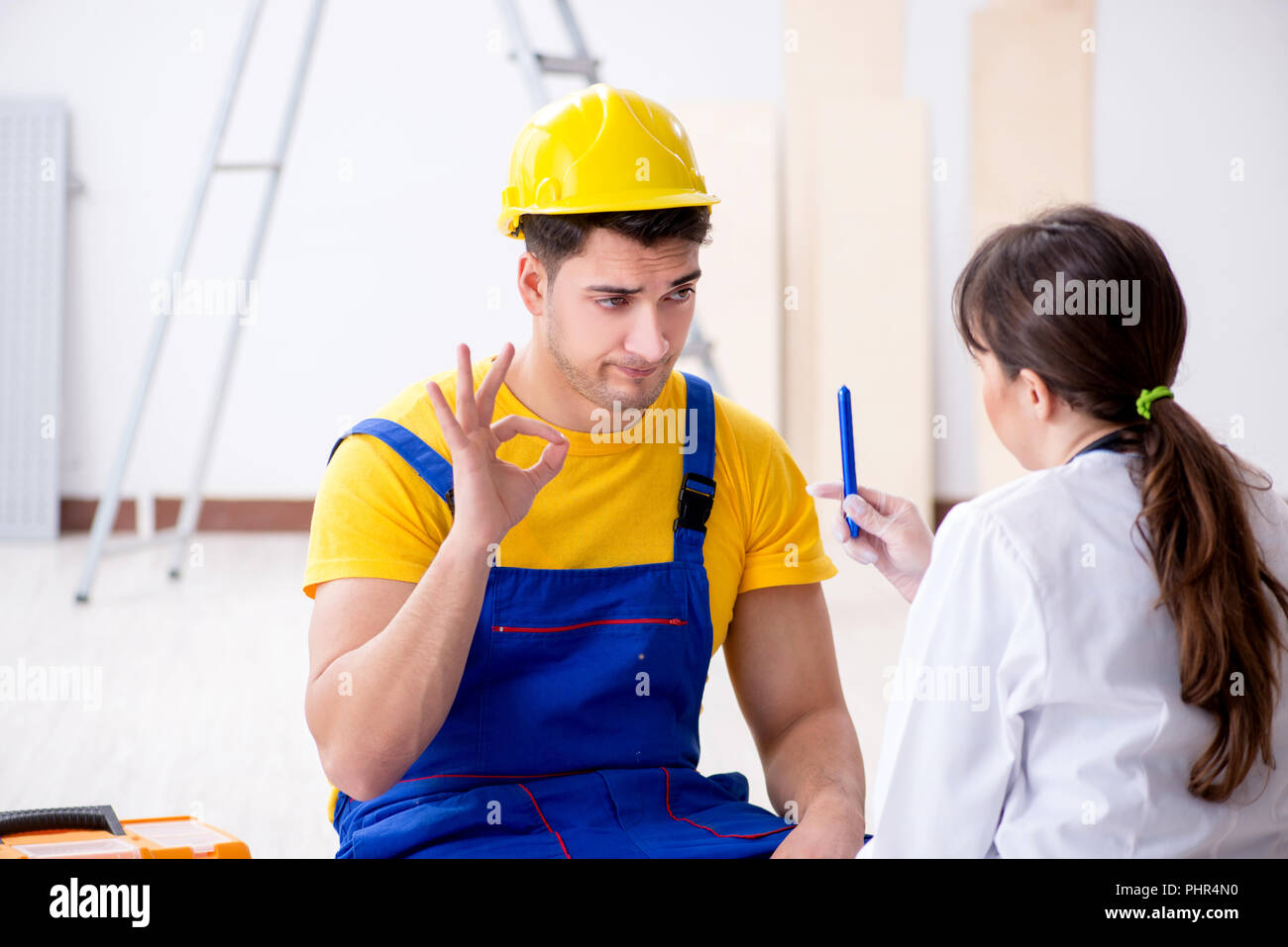 Doctor helping injured worker at construction site Stock Photo - Alamy