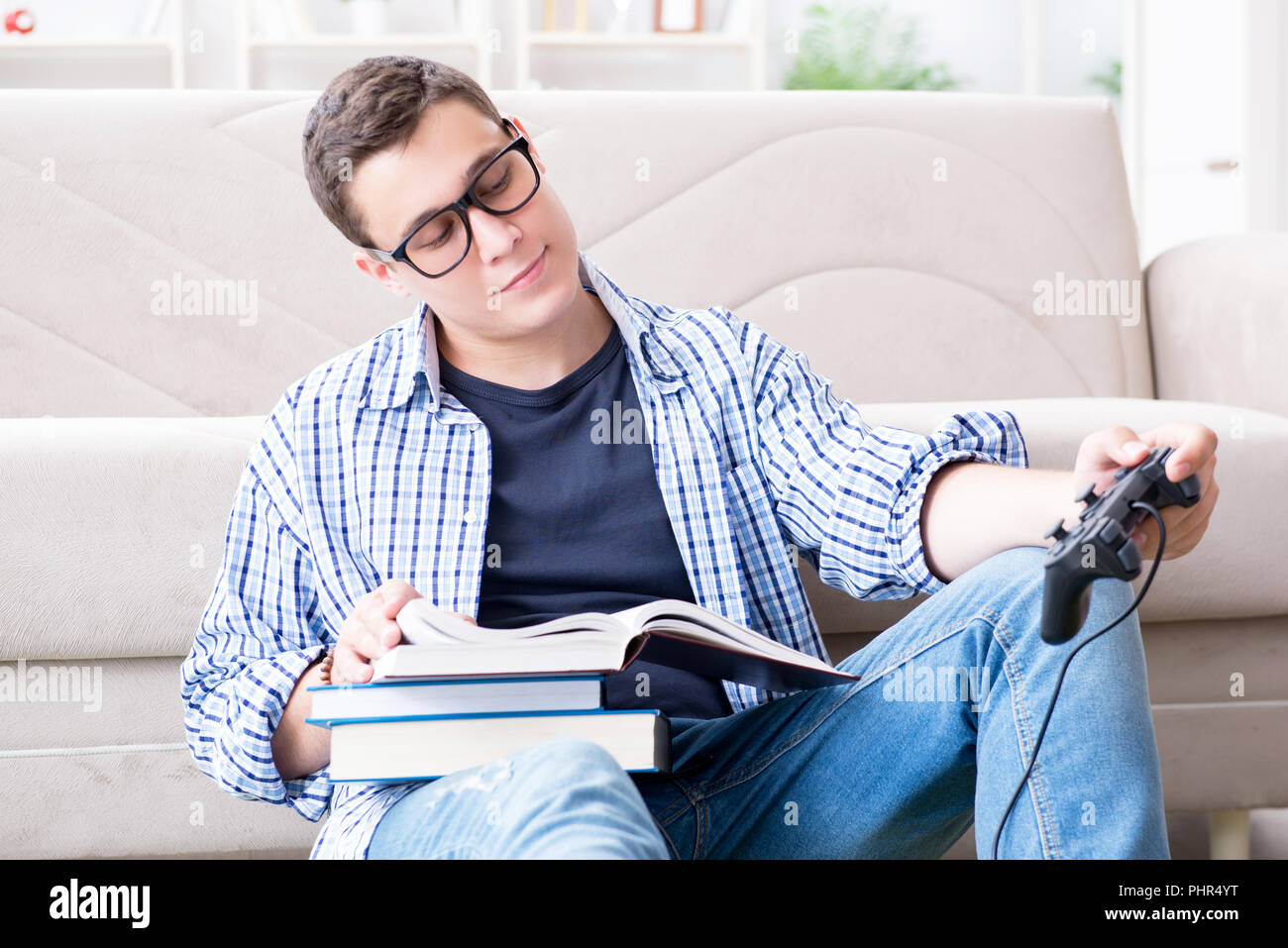 Young student trying to balance studying and playing games Stock Photo ...