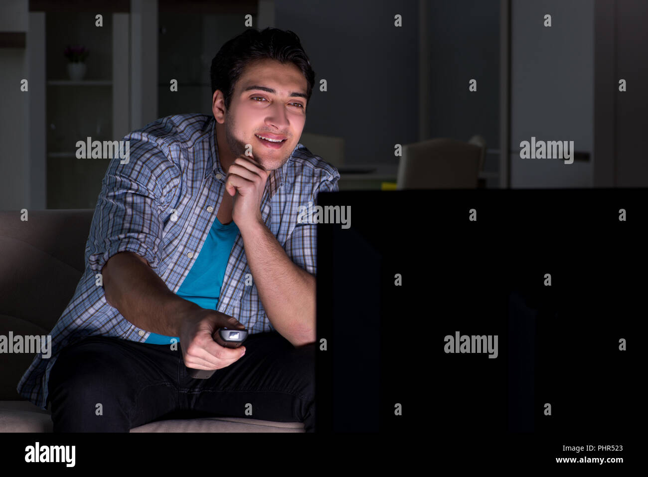 Young man watching tv late at night Stock Photo - Alamy