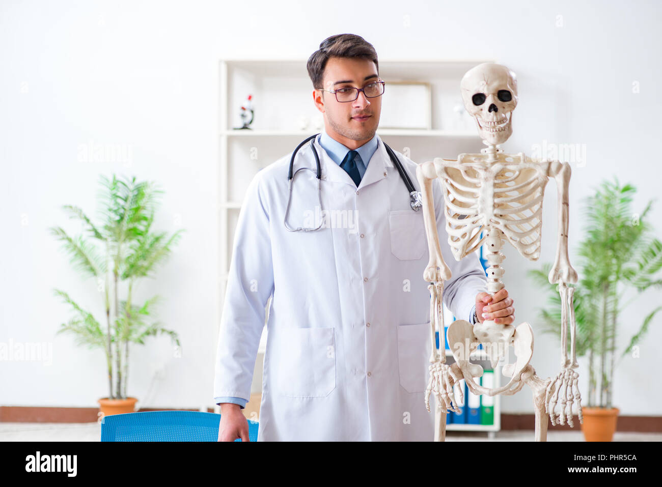 Yong male doctor with skeleton isolated on white Stock Photo - Alamy