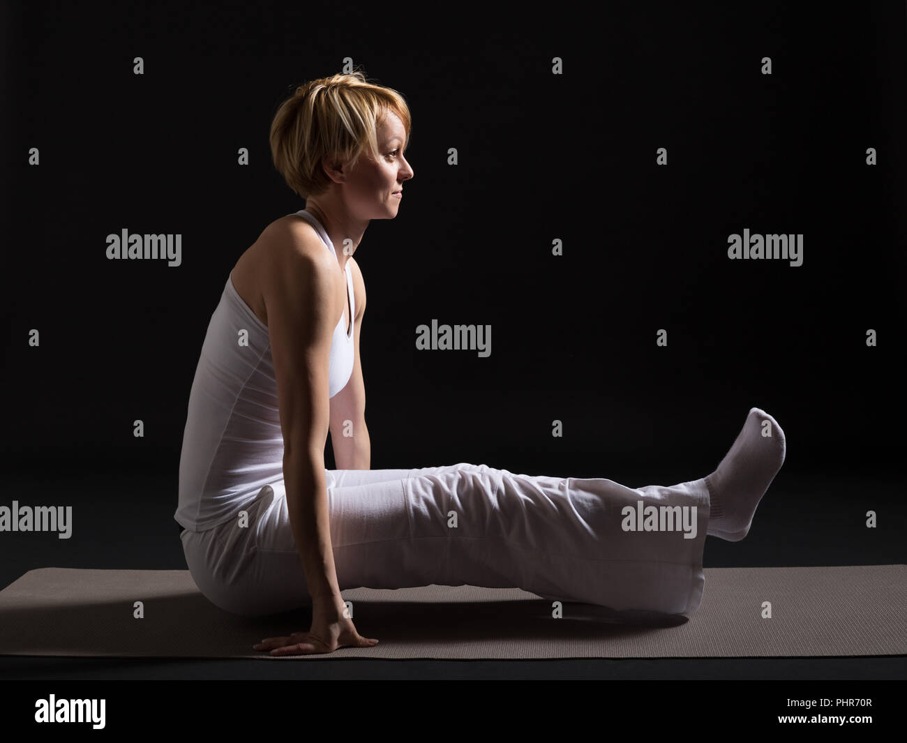 Woman exercising yoga indoor on black background,Balance pose/Tulasana ...
