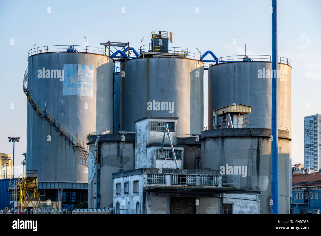 Silos of storage of silver color and old factory structure in front of ...