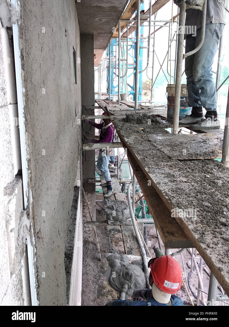 Construction workers plastering wall using cement plaster at the ...