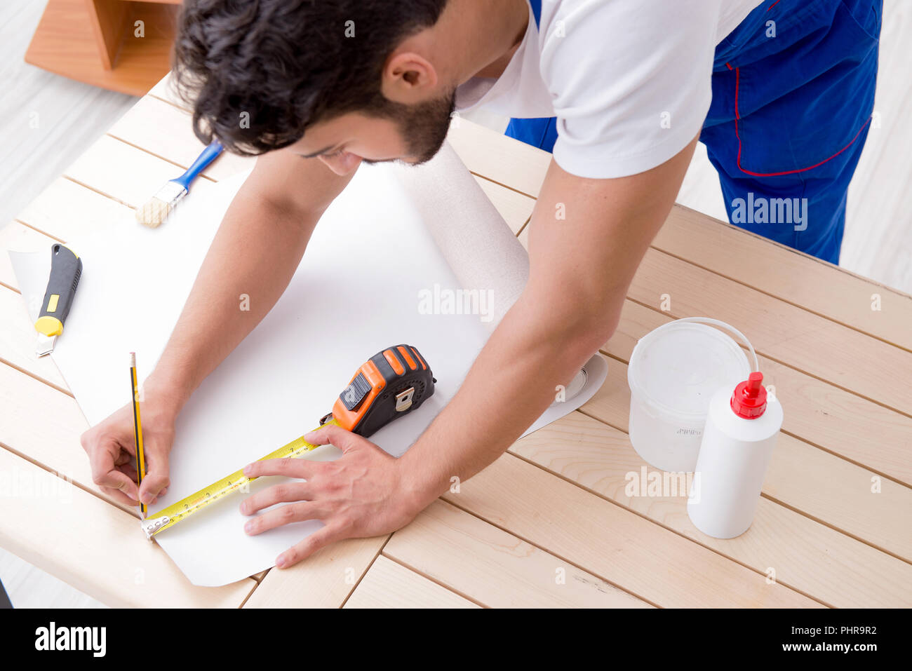 Worker working on wallpaper during refurbishment Stock Photo - Alamy