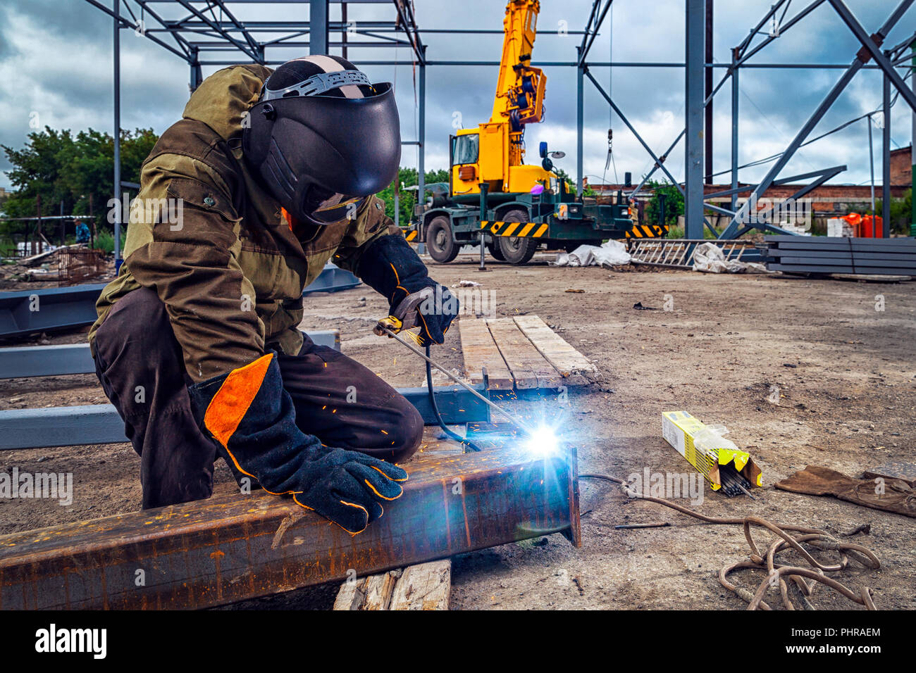 Man welder in welding mask, building uniform and blue protective gloves ...