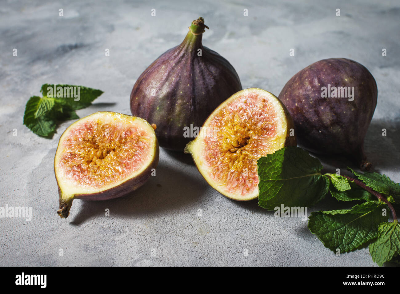 Ripe sweet figs with green leaves on concrete background Stock Photo ...