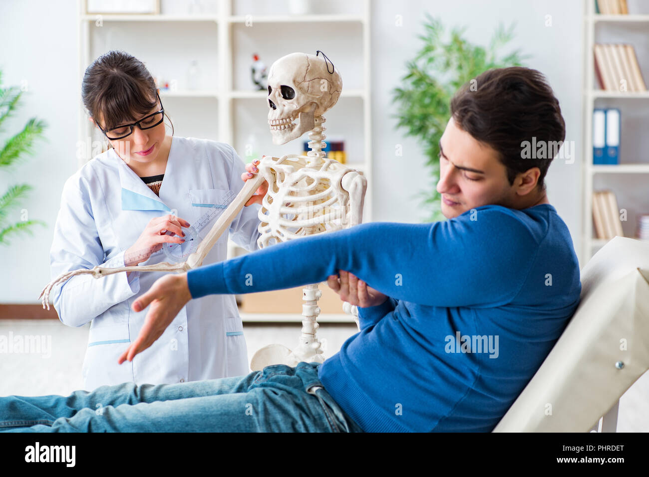 Doctor showing type of injury on skeleton to patient Stock Photo - Alamy