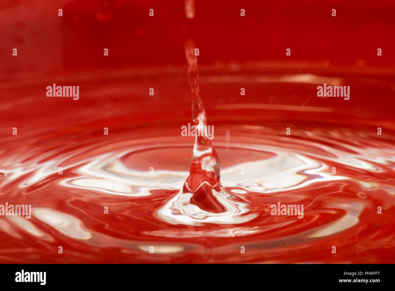 Water drop on a red background Stock Photo - Alamy