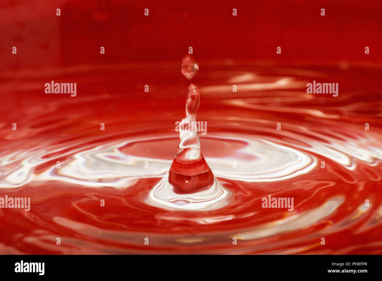 Water drop on a red background Stock Photo - Alamy