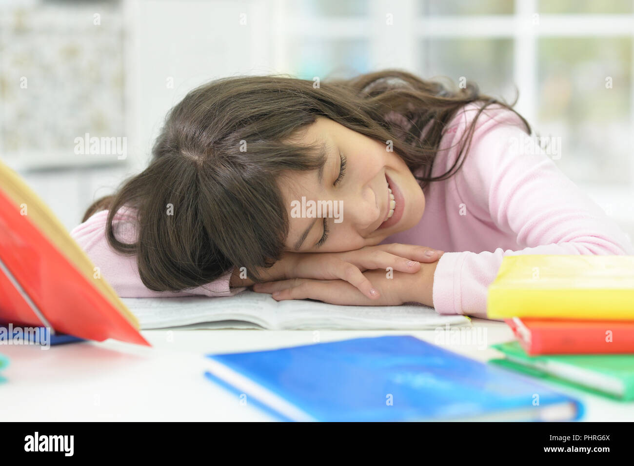Portrait of a smiling schoolgirl resting at desk after studying Stock ...