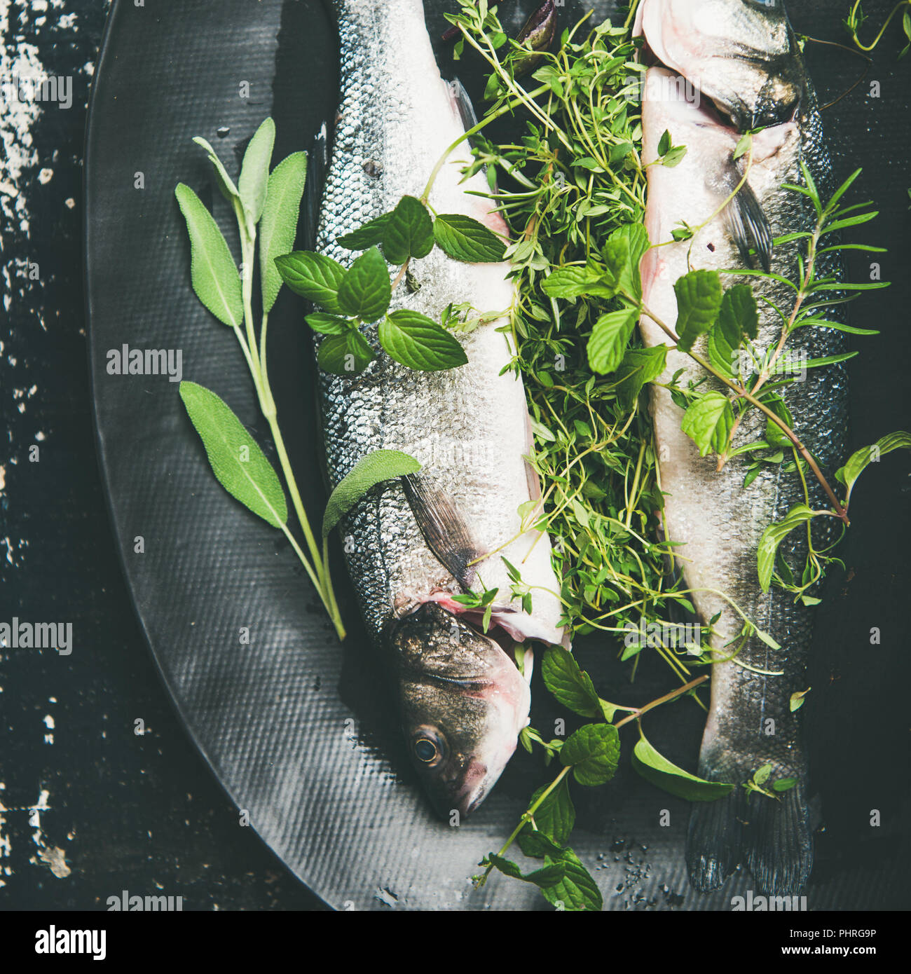 Flat-lay of raw uncooked sea bass with herbs, square crop Stock Photo ...