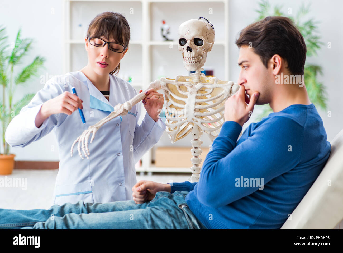 Doctor showing type of injury on skeleton to patient Stock Photo - Alamy