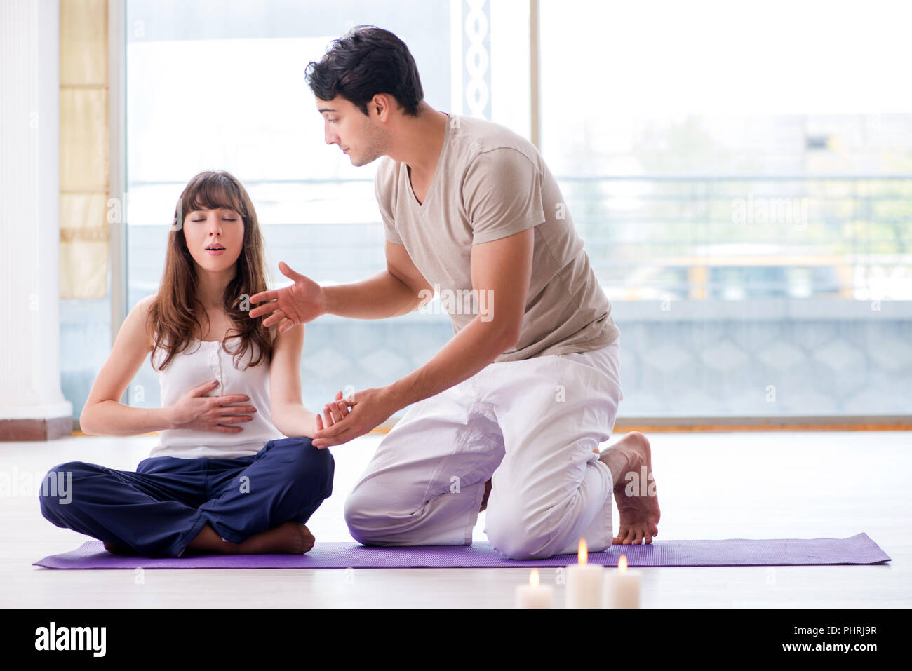 Personal coach helping during yoga session Stock Photo - Alamy