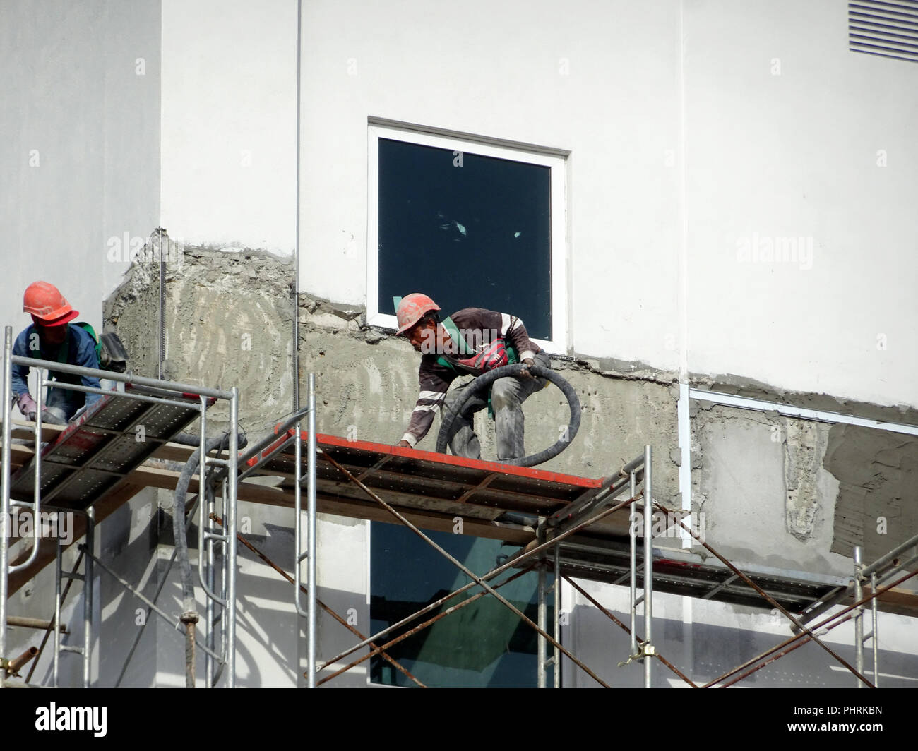 Construction workers plastering wall using cement plaster at the ...