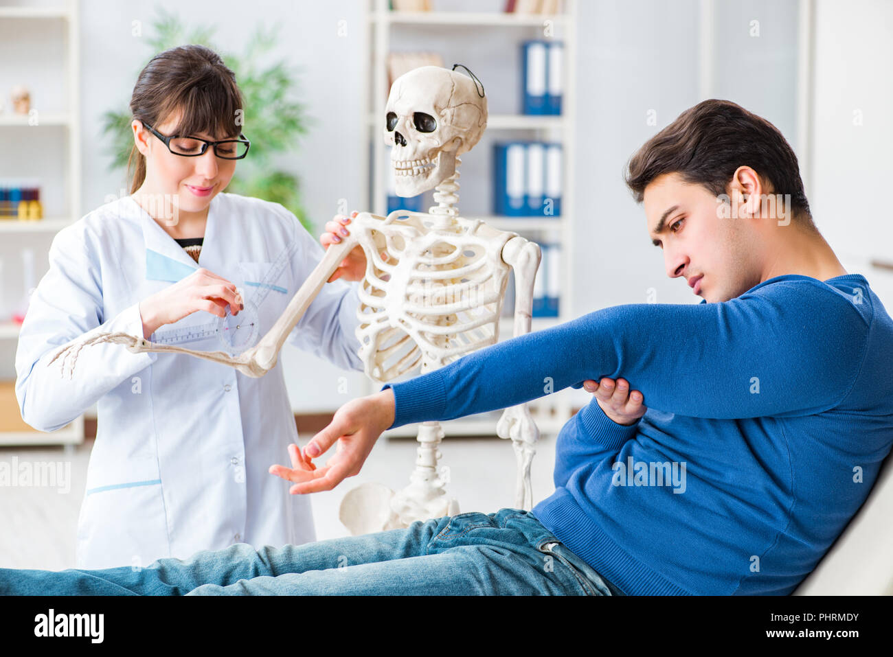 Doctor showing type of injury on skeleton to patient Stock Photo - Alamy