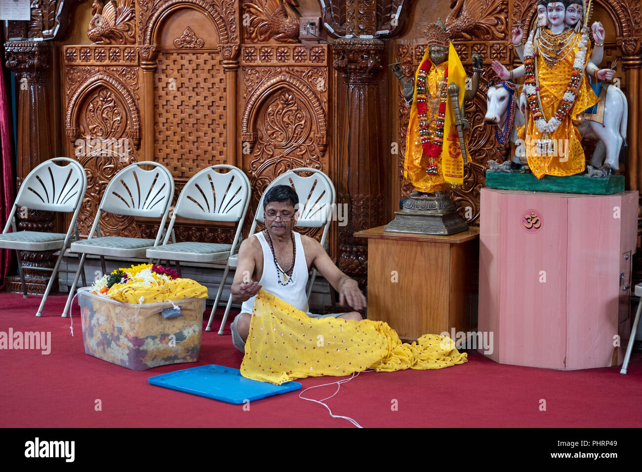 An Indian worker at the Geeta temple sewing costumes that will be put ...