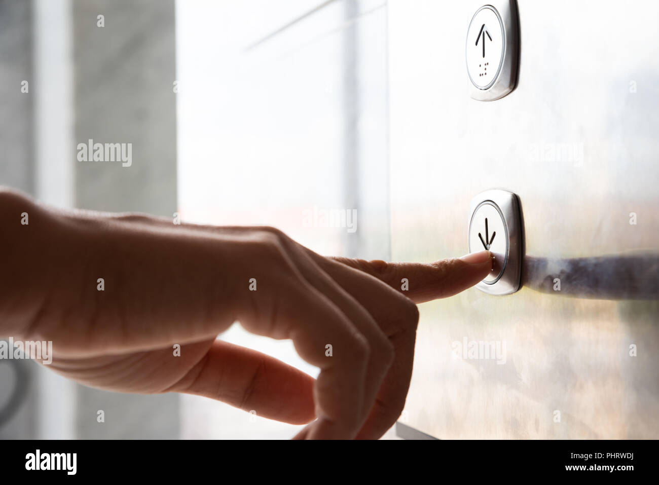 Close up waman hand press a down button of elevator inside the building ...