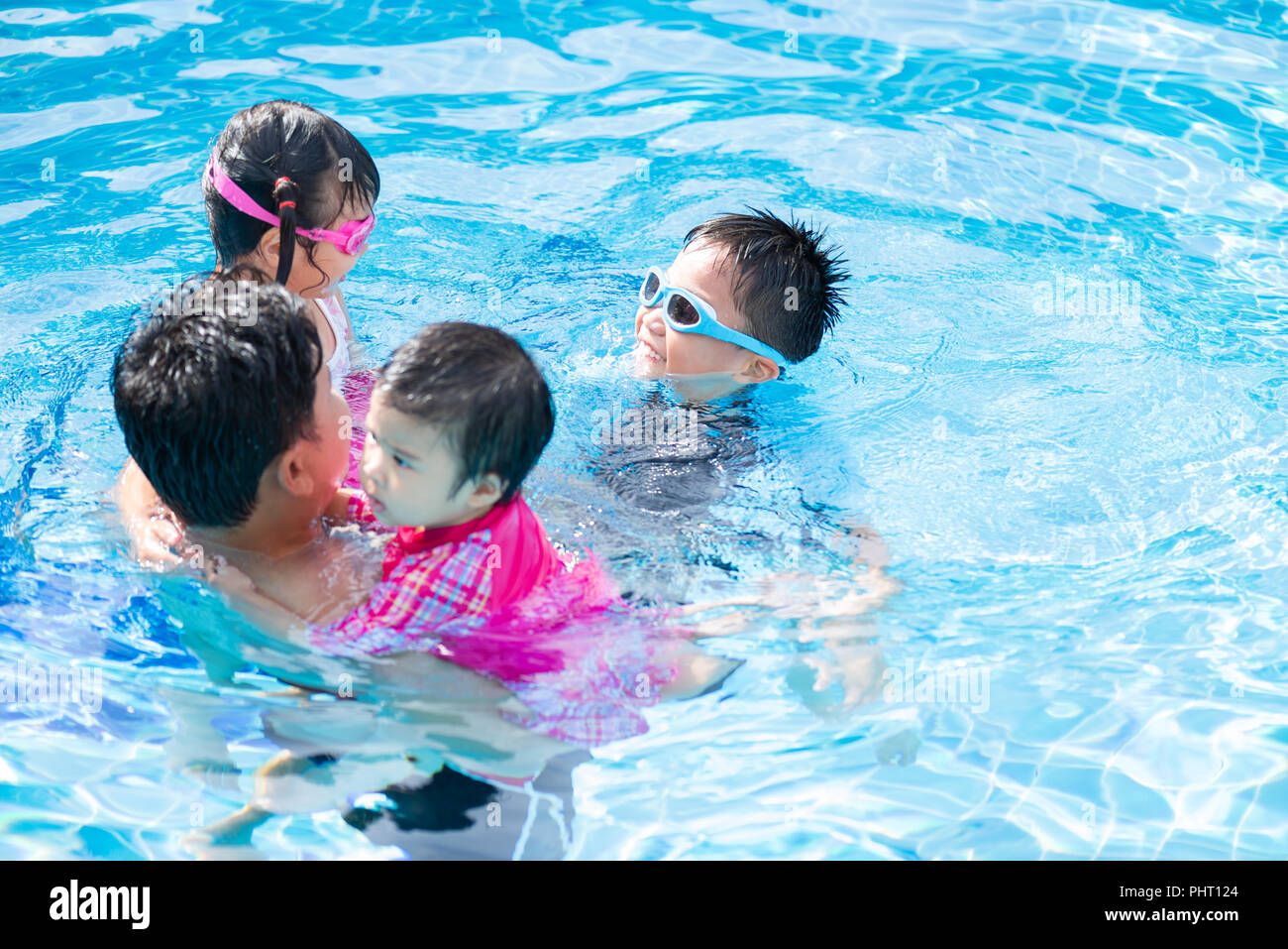 Happy family with kids having fun in swimming pool. Smiling parents and ...