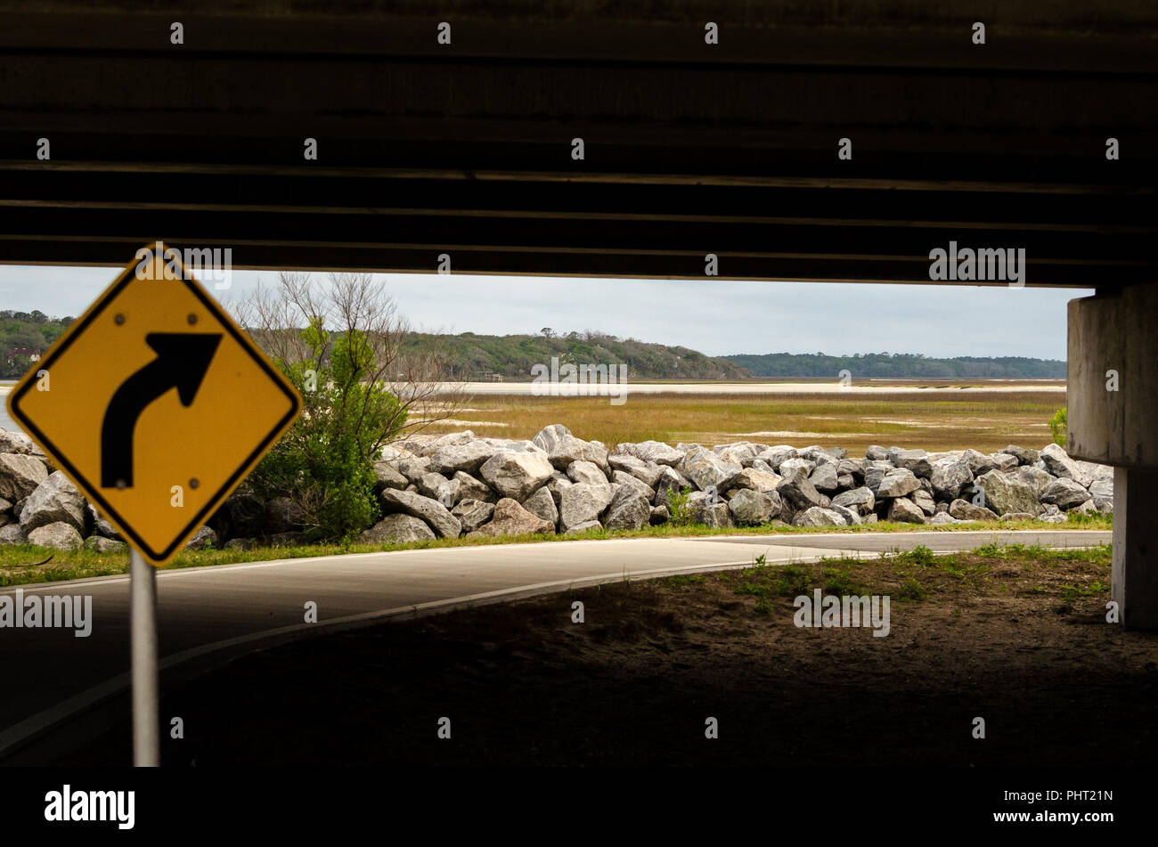 Turn sign at a bicycle path under a bridge with marshland in the ...