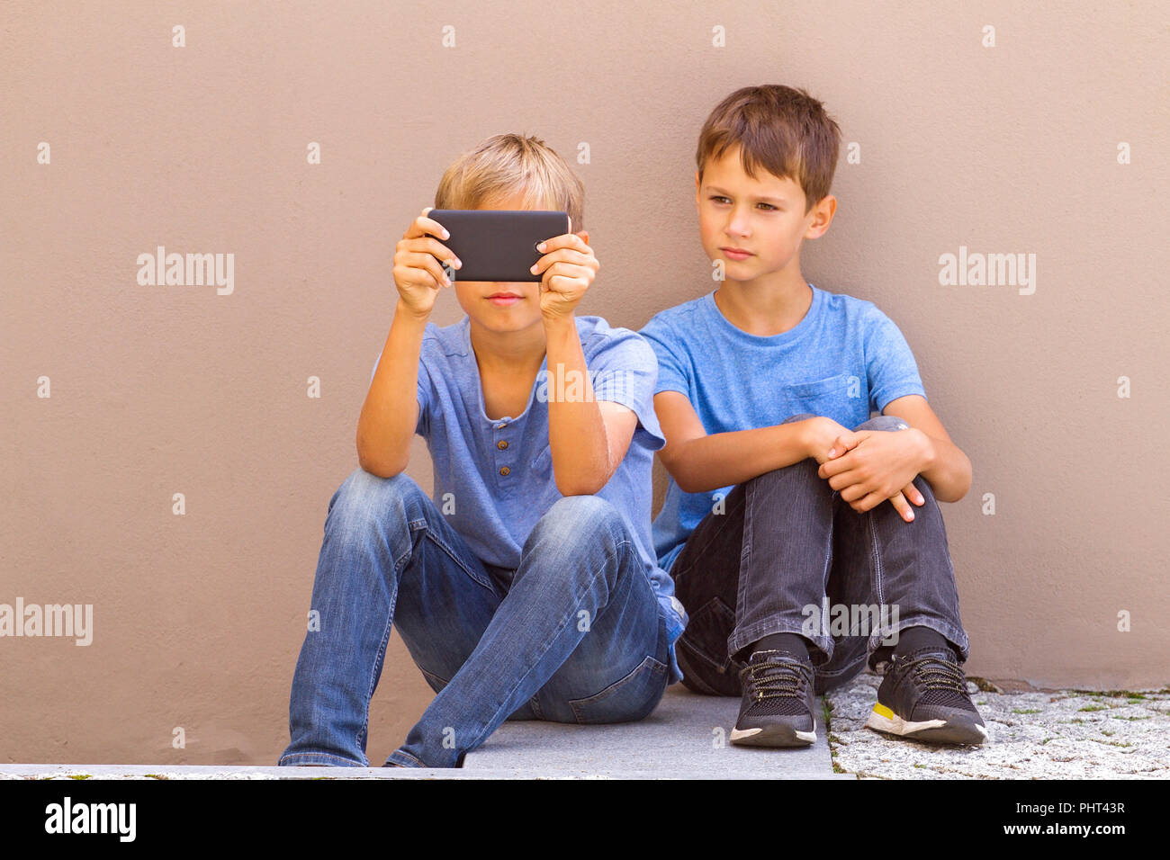 Kids sitting outside and playing games on smartphone Stock Photo - Alamy