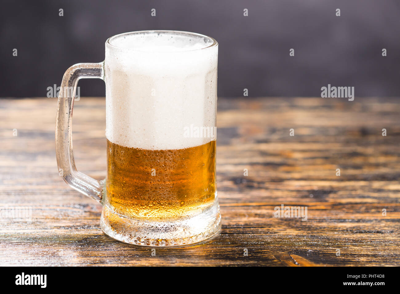 Cold glass of lager beer with foam and dew on dark background with copy ...