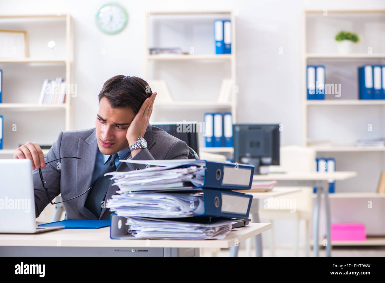 Overloaded with work employee under paperwork burden Stock Photo - Alamy