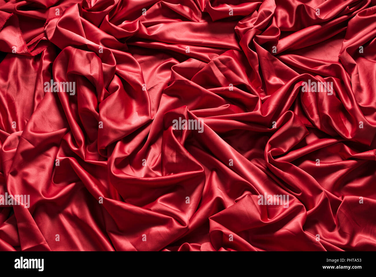Red silk textured fabric with glitter folded folds with deep shadows ...