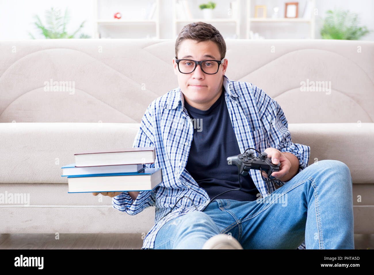 Young student trying to balance studying and playing games Stock Photo ...