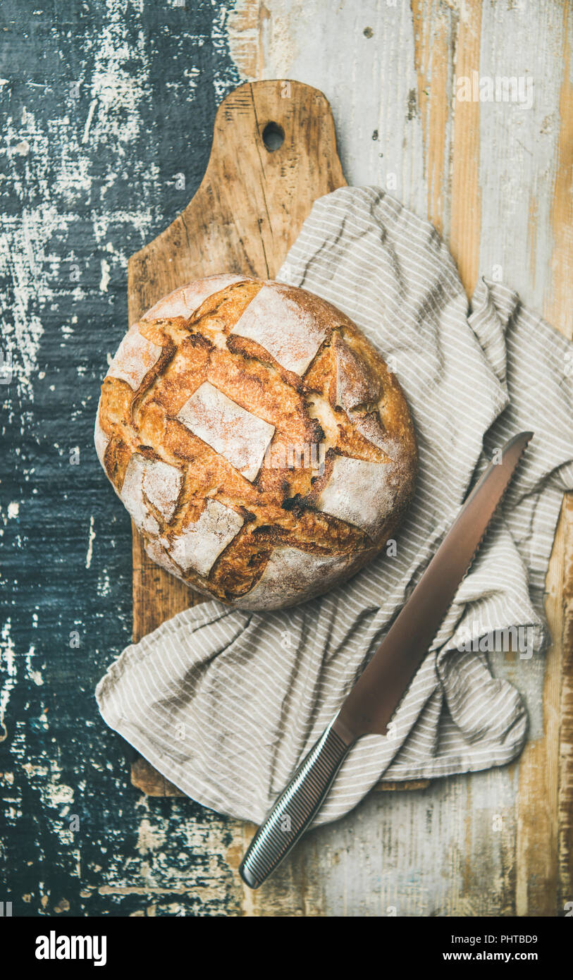 Flat-lay of freshly baked sourdough wheat bread loaf on board over ...