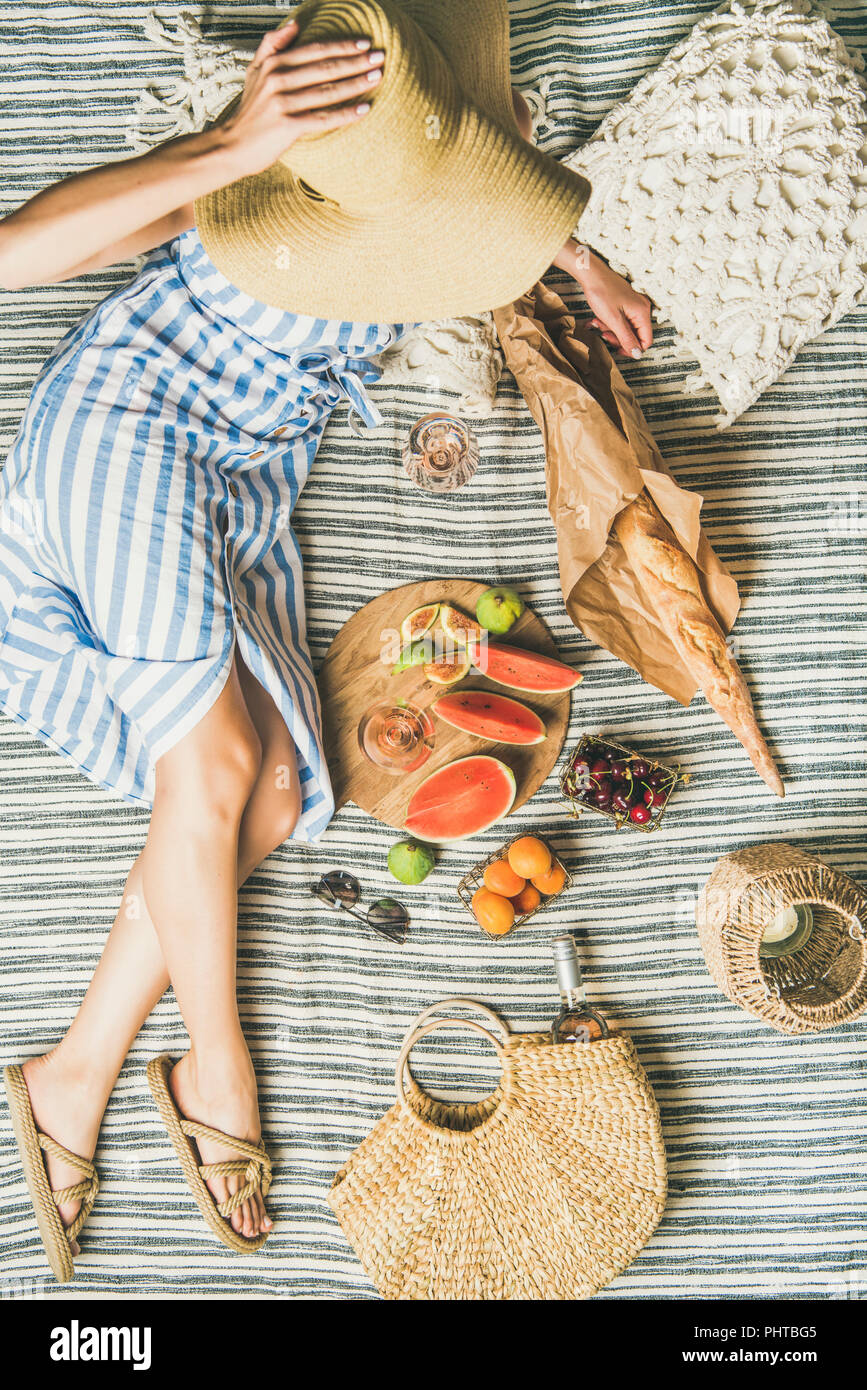 Summer picnic setting. Young woman in striped dress and straw sunhat ...