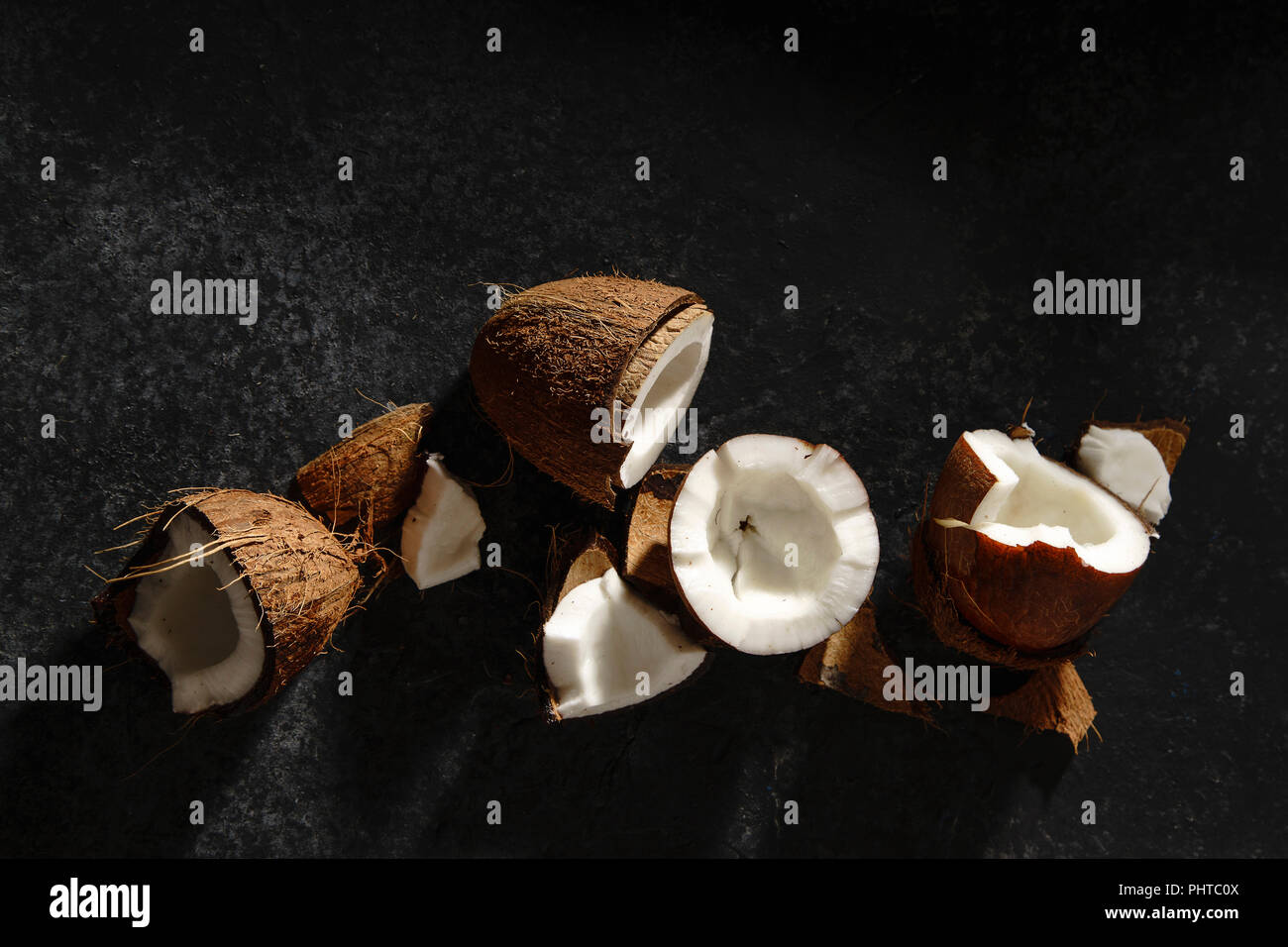 Cracked coconut arranged on dark textured background. Hard light Stock ...